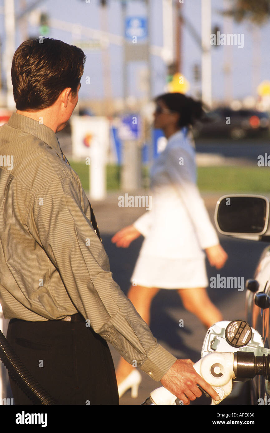 Man at gas pump in California self serve gas station watching passing ...