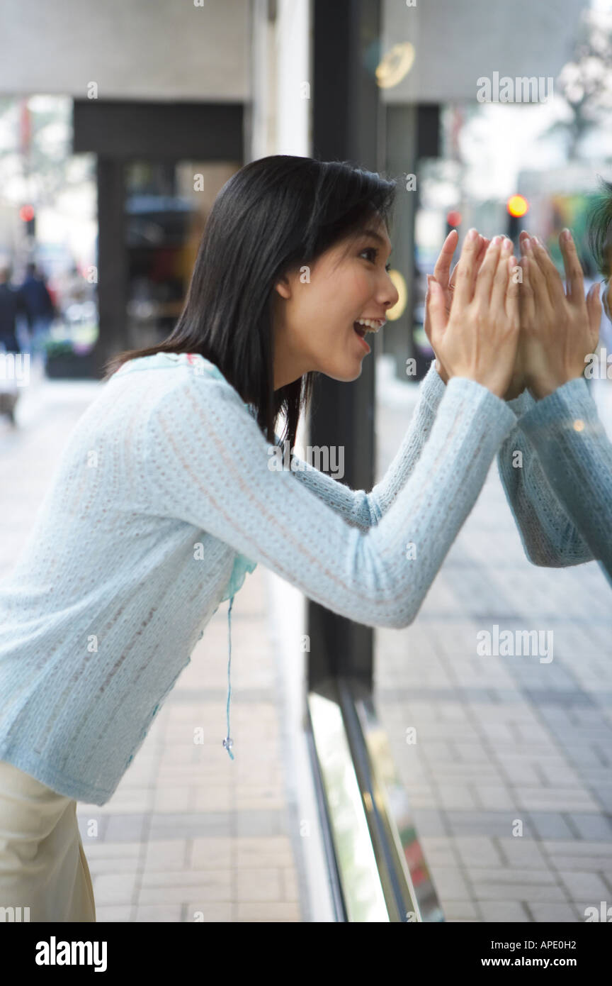 Young woman looking through the window with big desire for something ...