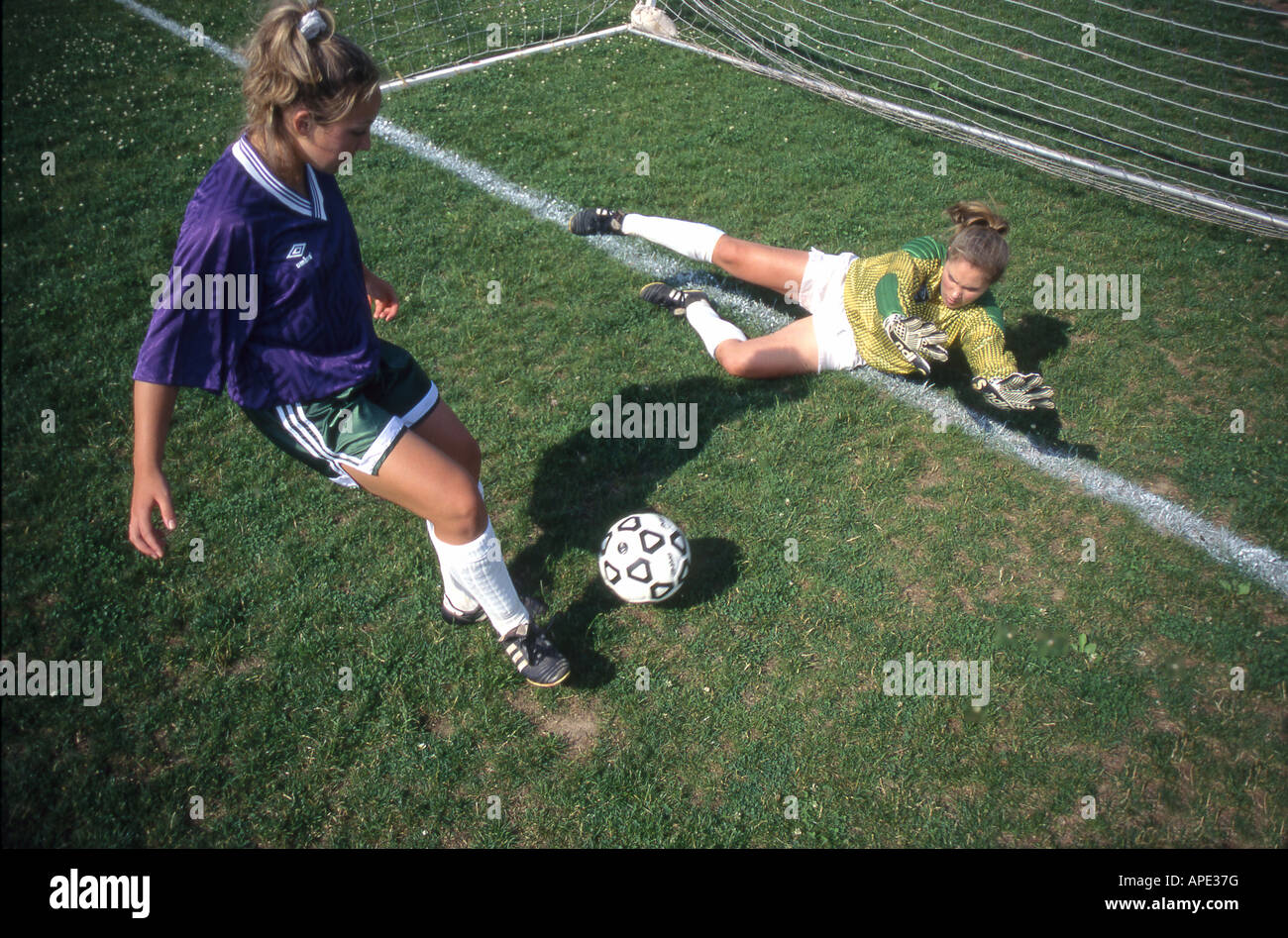 Teen girl blocks soccer opponents goal kick Stock Photo - Alamy