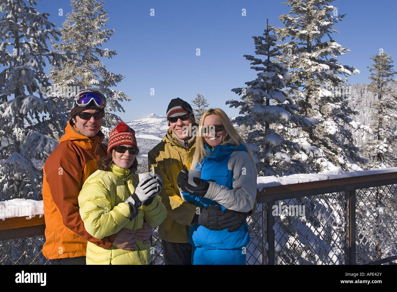 Friends smiling and drinking hot chocolate on a snowy deck in winter at ...