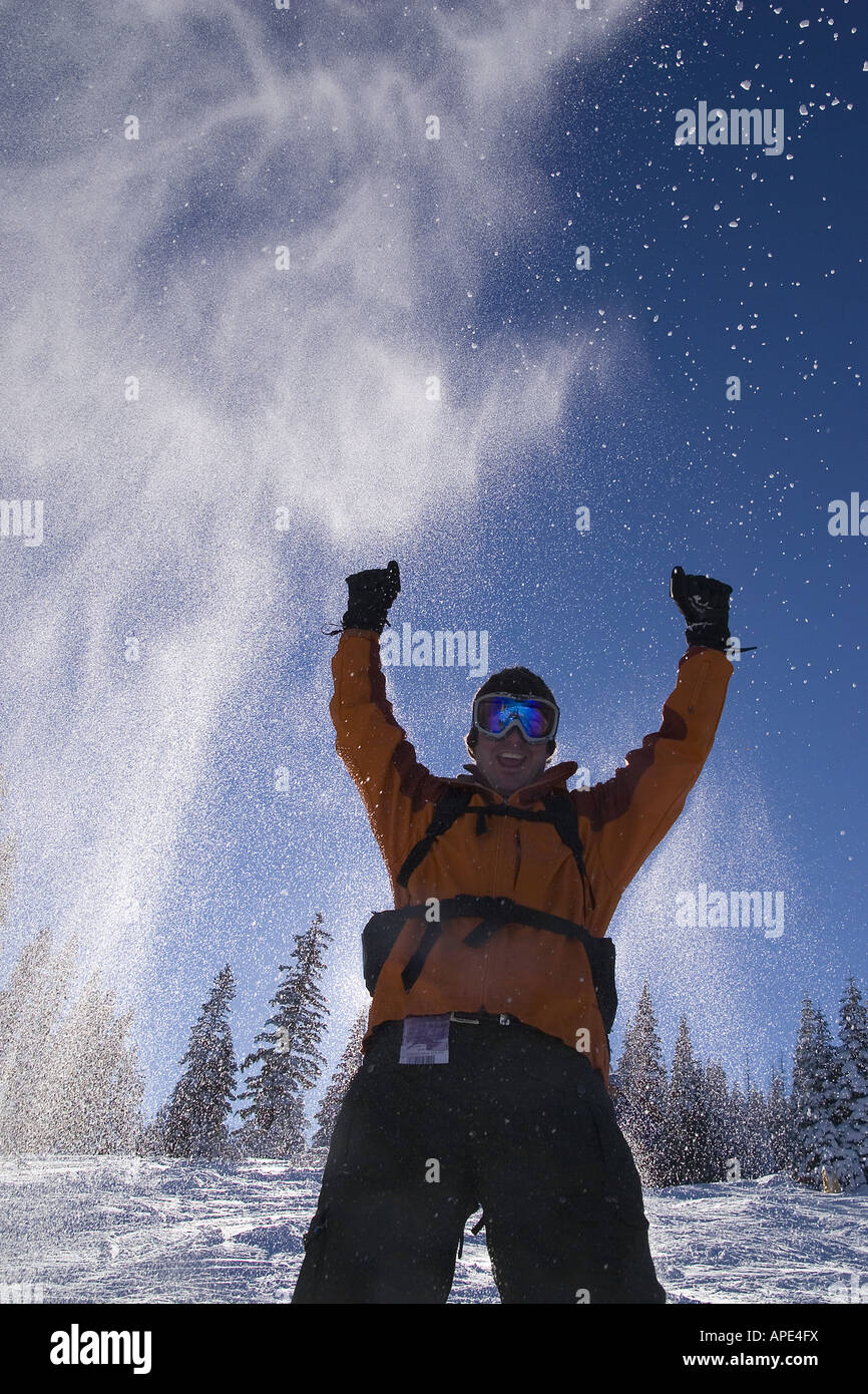 A happy snowboarder throwing his arms into the air in the snow at ...