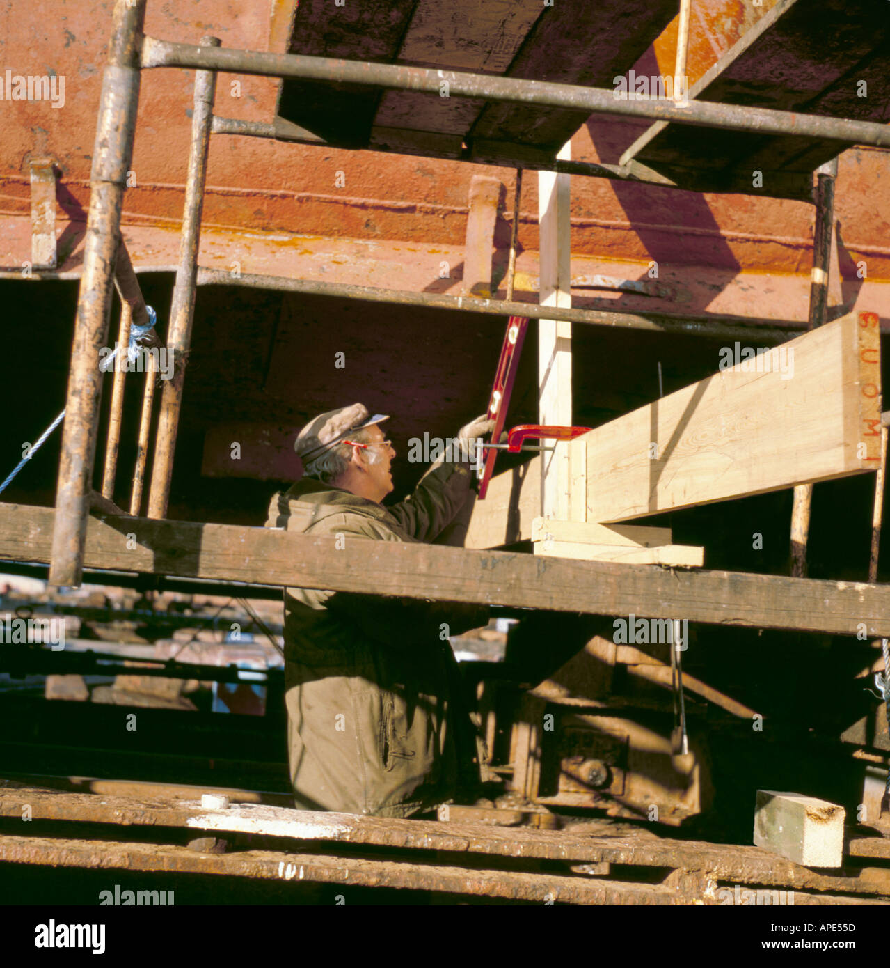 Shipwright using a spirit level whilst erecting timbers to check the ...