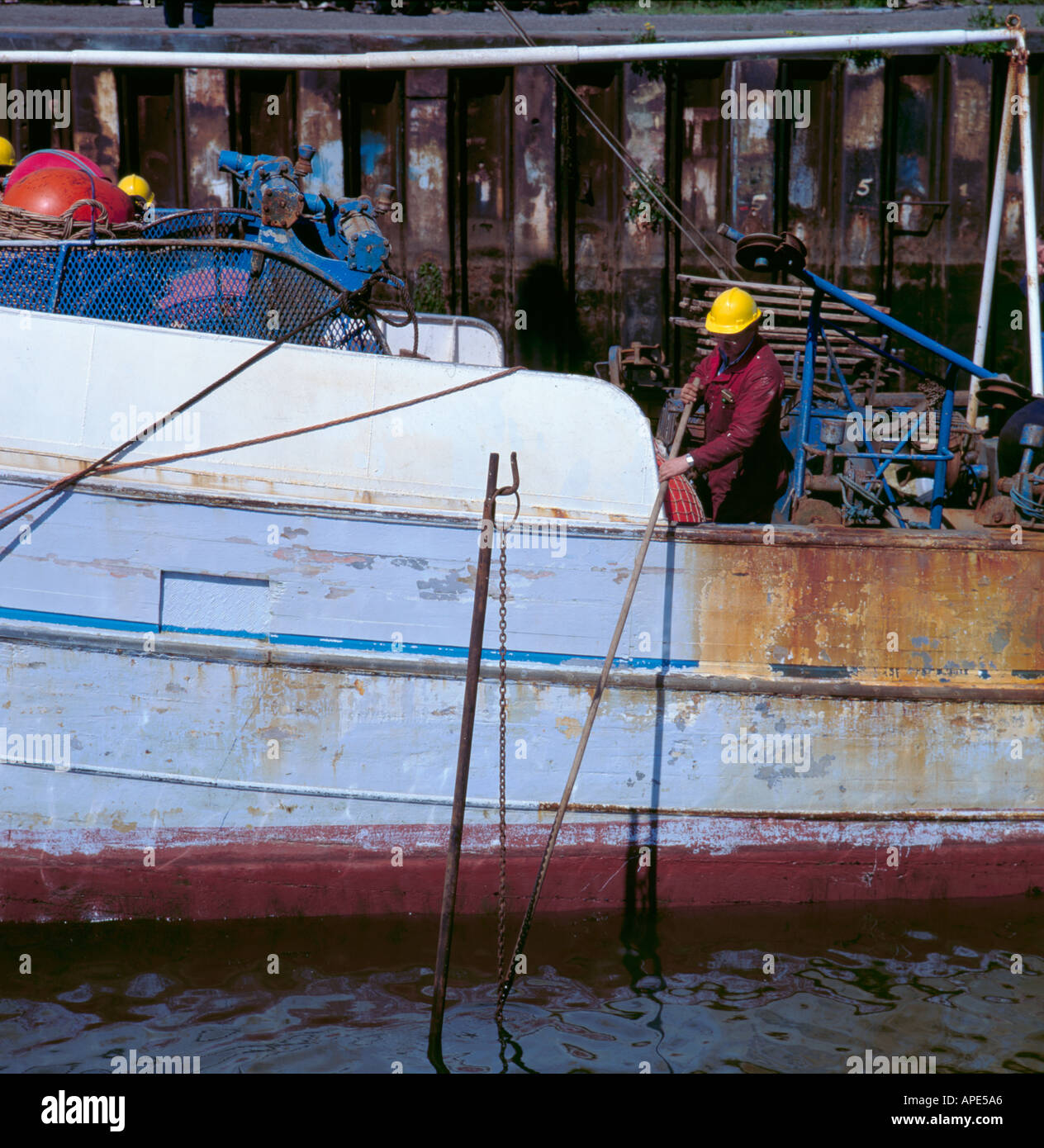 Ship repair and maintenance; man locating chain of a slipway cradle bar ...