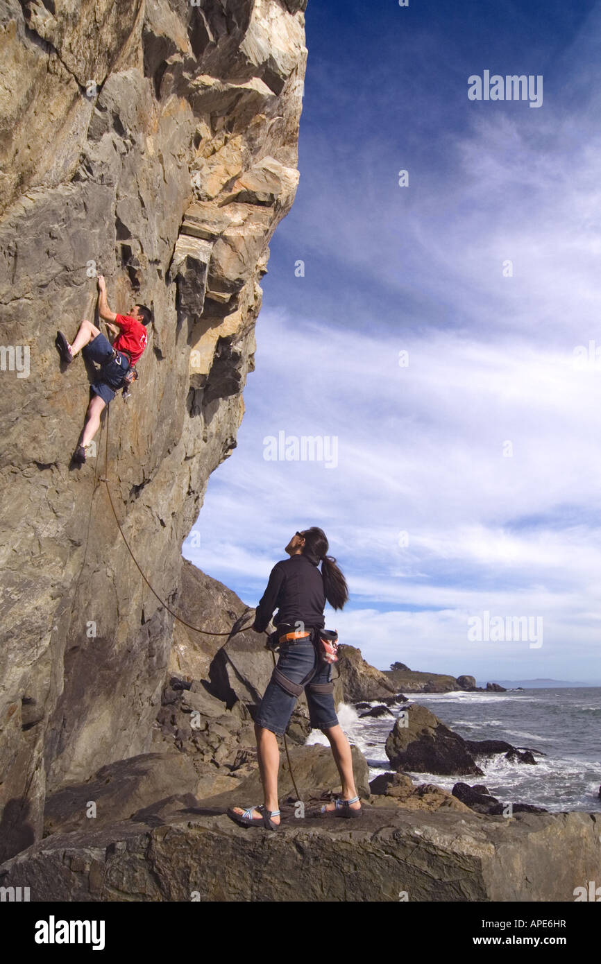 A man and a woman rock climbing next to the Pacific Ocean at Mickey's ...