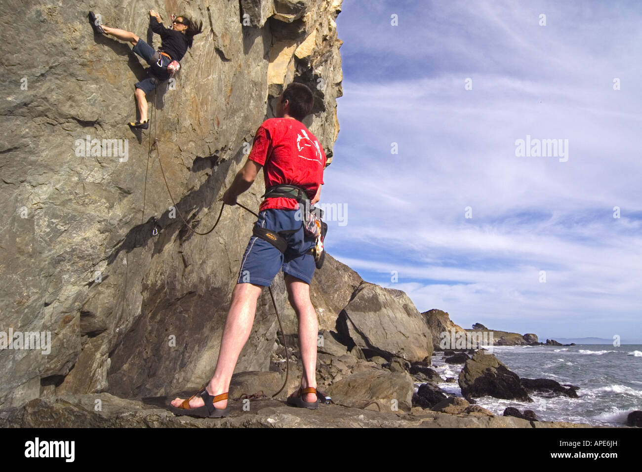A man and a woman rock climbing next to the Pacific Ocean at Mickey's ...