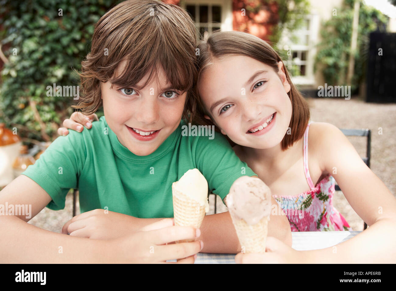 Two Kids Eating Ice Cream Cones at table in back yard, portrait Stock ...