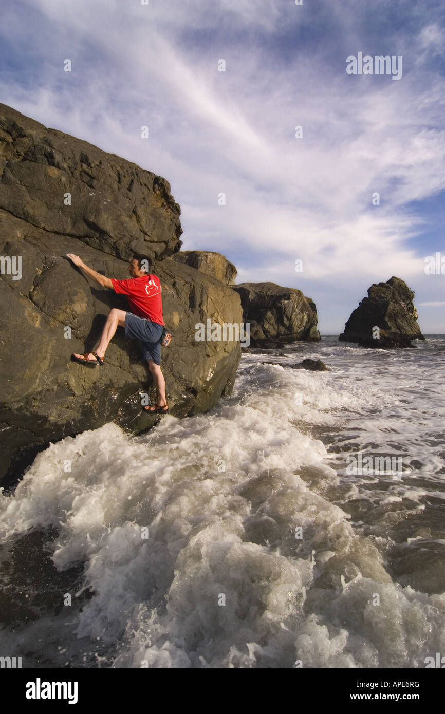 A man rock climbing next to the Pacific Ocean at Mickey's Beach near ...