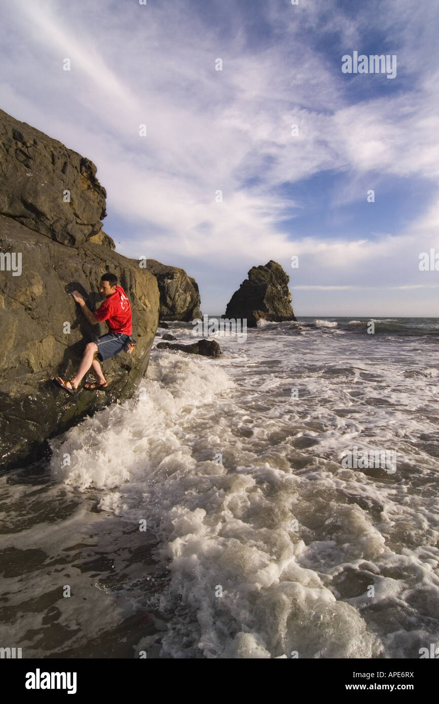 A man rock climbing next to the Pacific Ocean at Mickey's Beach near ...