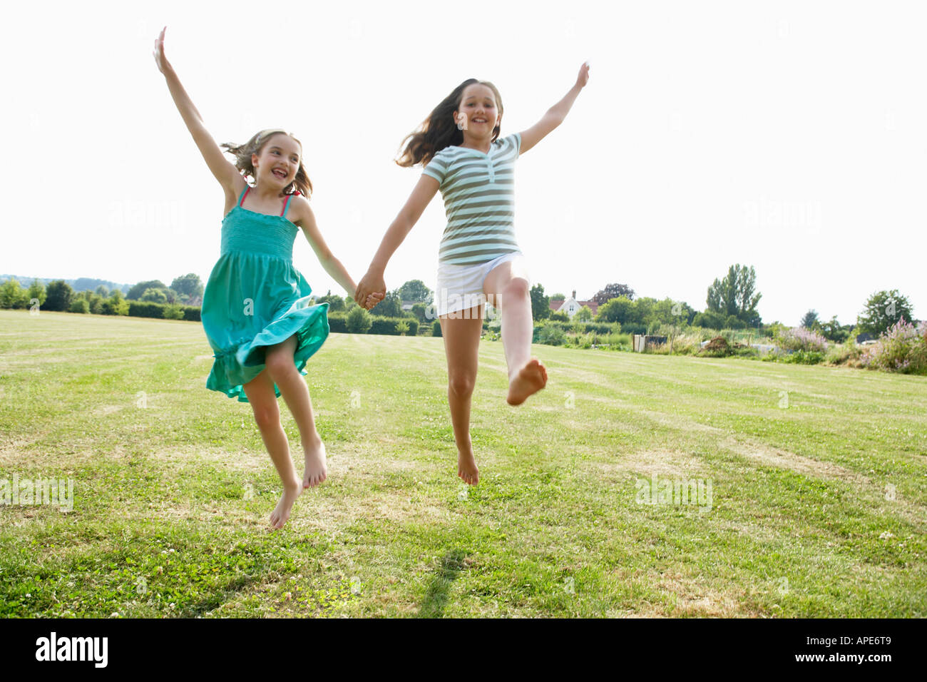 Girls Running and jumping Hand in Hand through field Stock Photo - Alamy