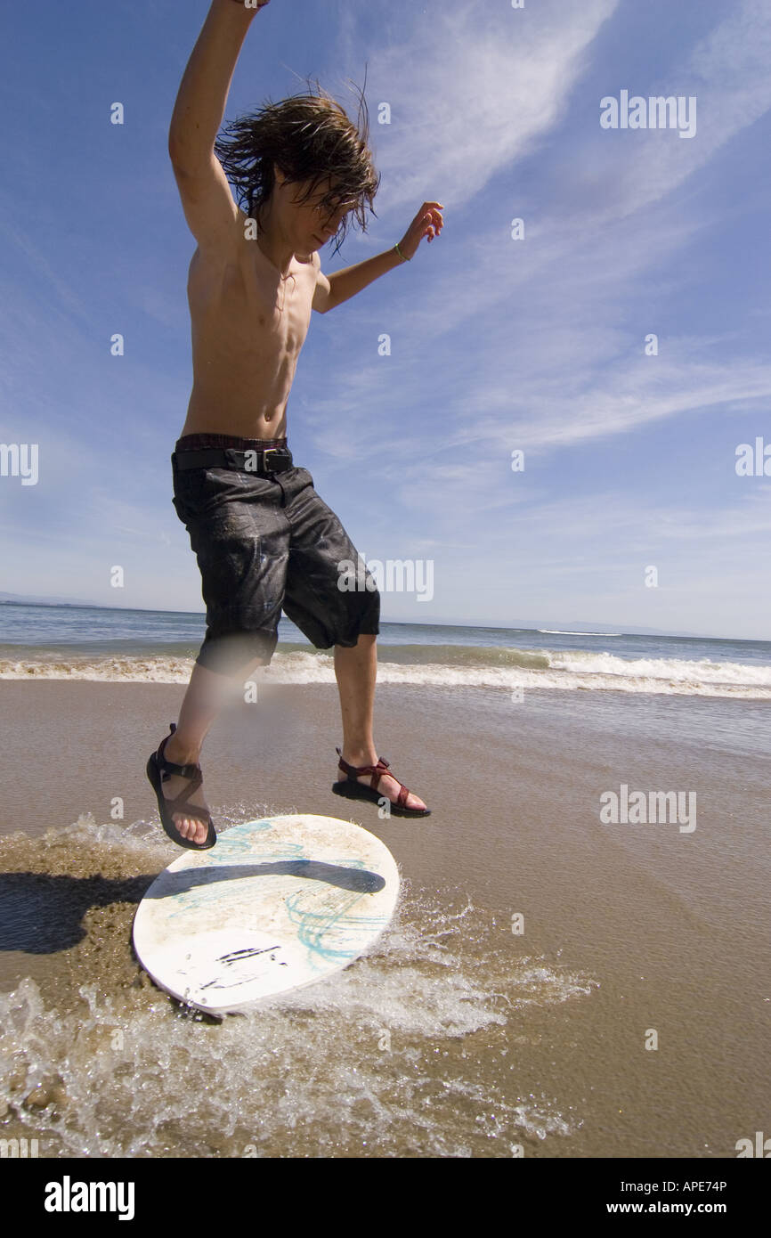 A young boy skim boarding on the beach on the Pacific Ocean in Santa ...
