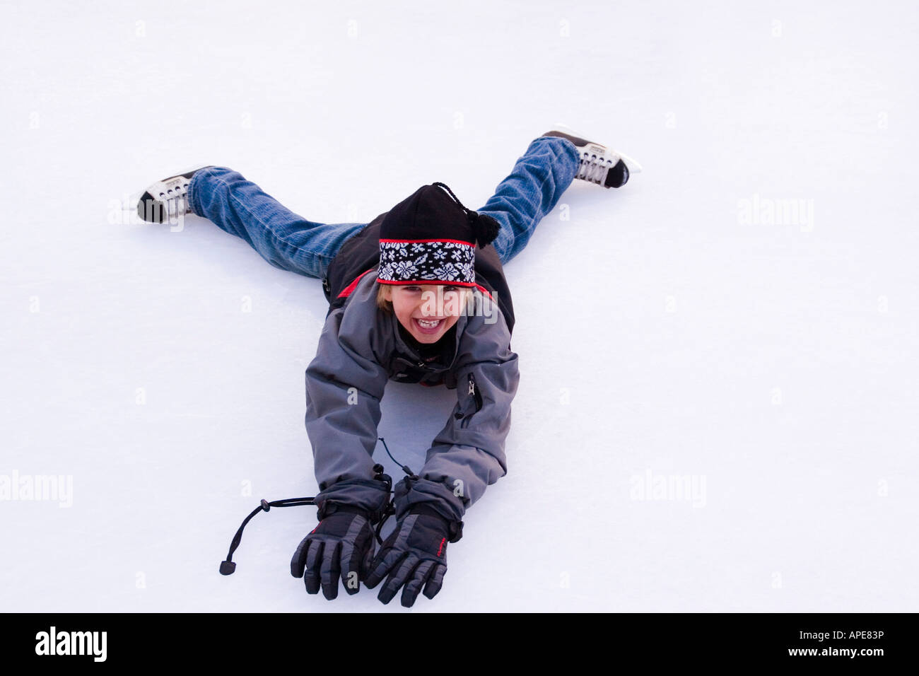 A young boy lying on the ice after falling while ice skating at ...