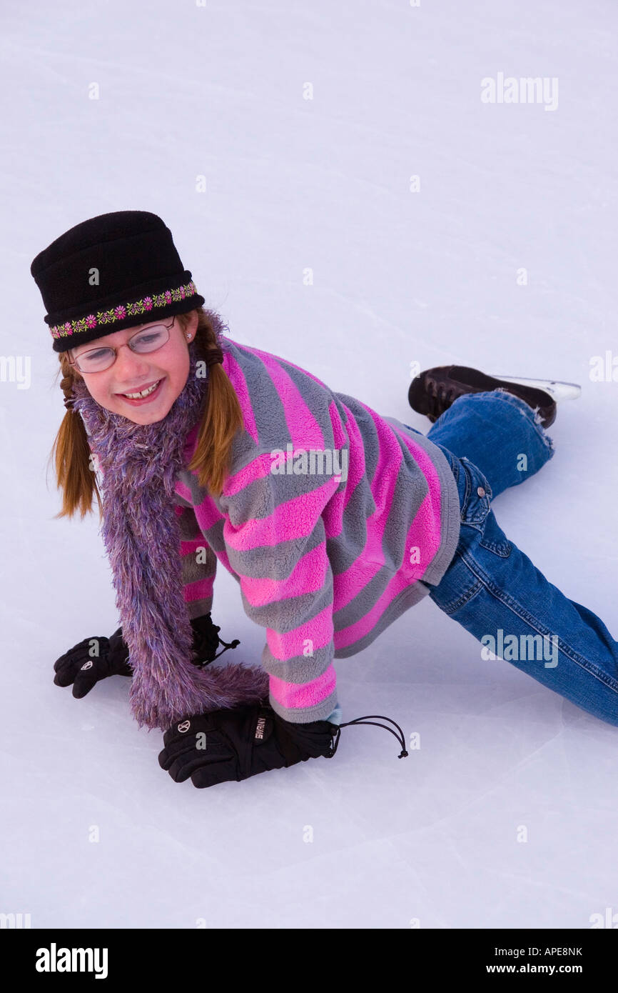 A smiling young girl lying on the ice at a skating rink at Northstar ...