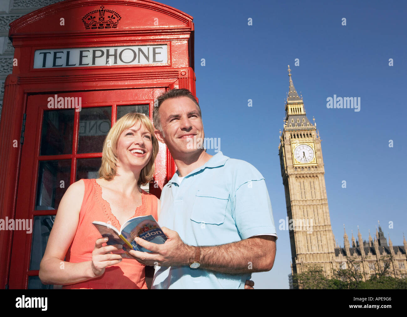 Couple with guidebook standing by London phone booth Stock Photo - Alamy