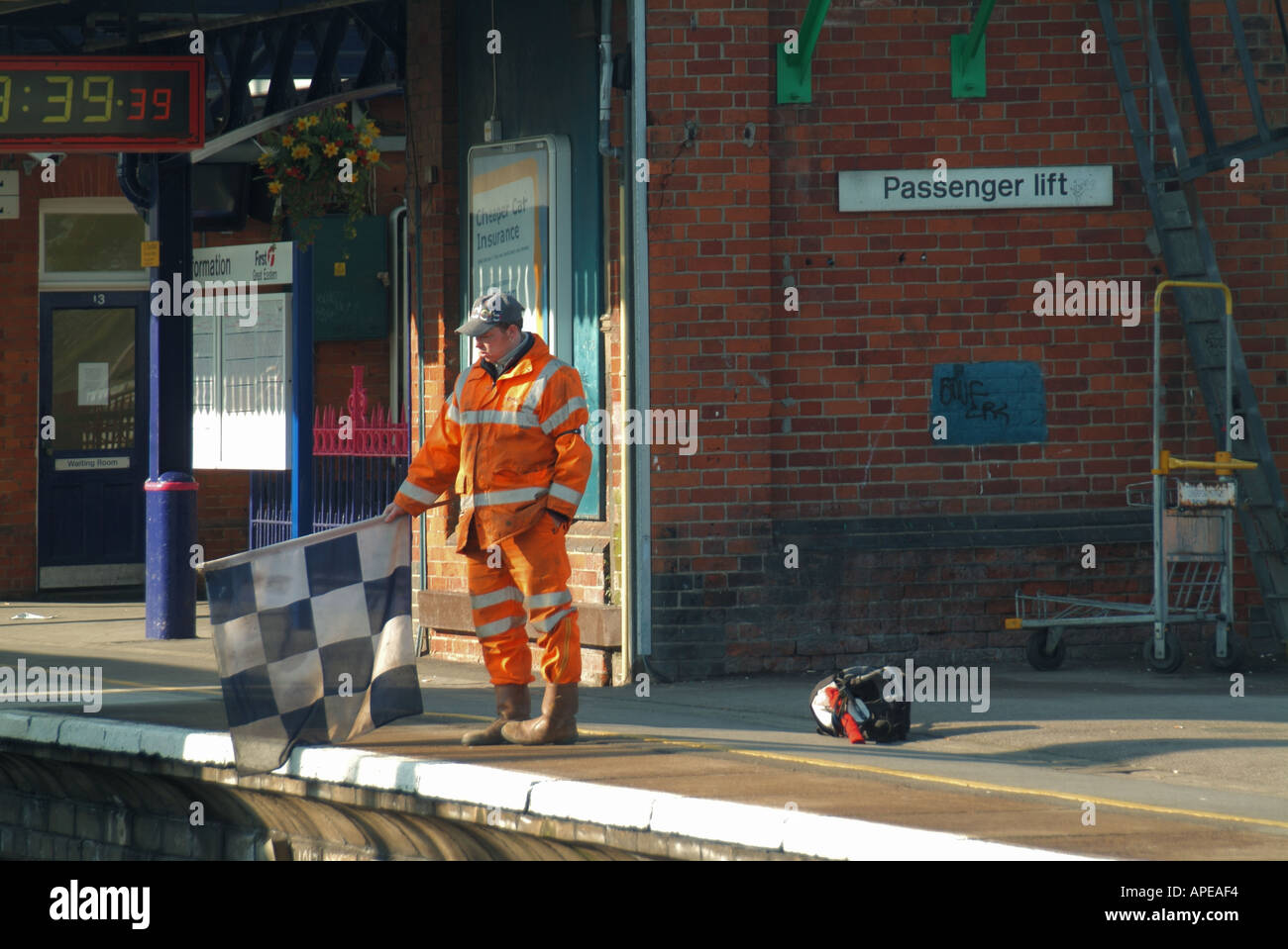Shenfield railway station platform with lookout holding out chequered ...