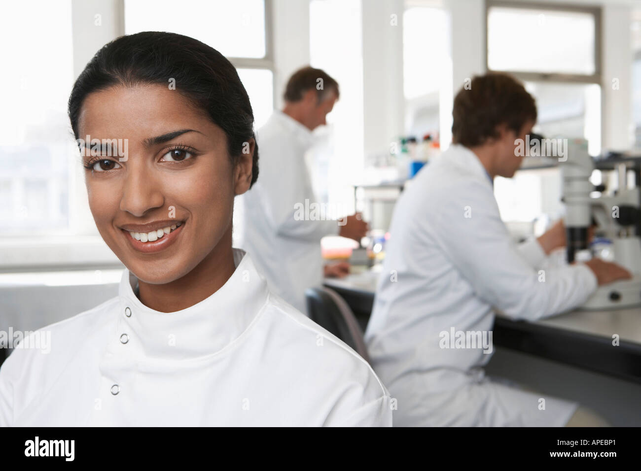 Smiling Lab Worker, colleagues behind Stock Photo - Alamy