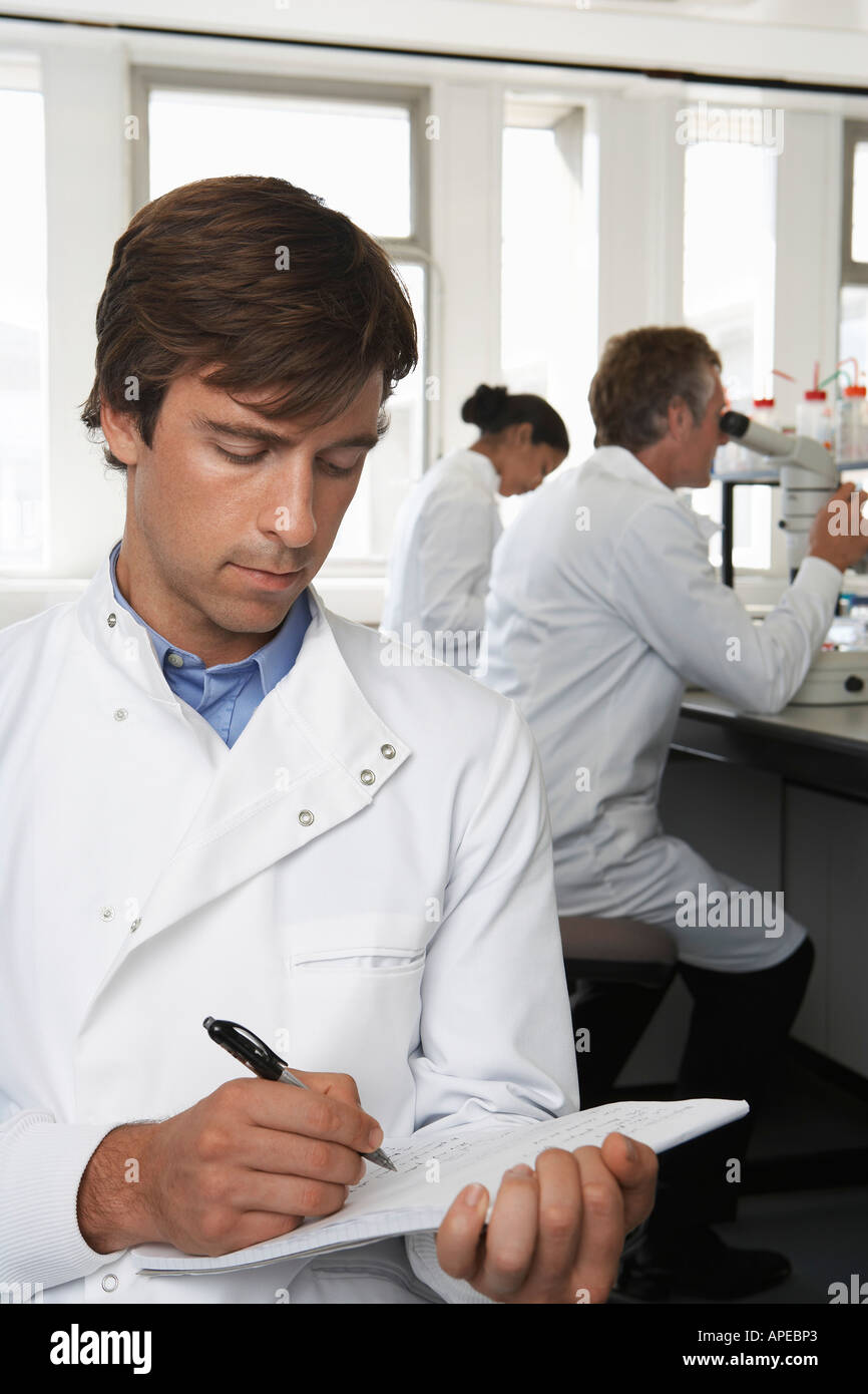 Lab Worker writing, colleagues behind Stock Photo - Alamy
