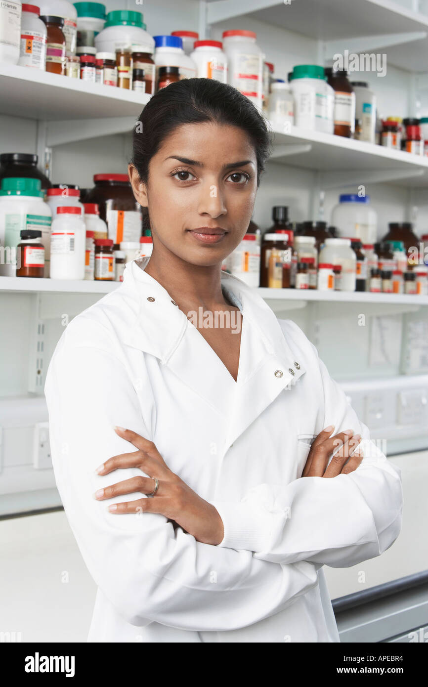 Female lab worker standing, pill bottles behind Stock Photo - Alamy
