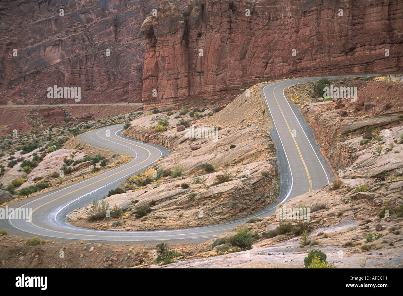 Twisting curves bend on two lane road below red rock cliffs Arches ...