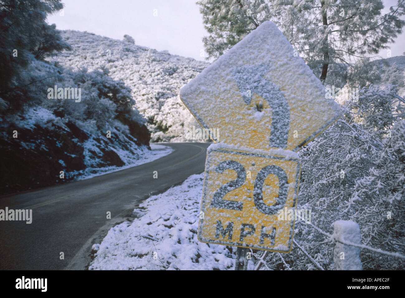 Winter snow on slow curve turn speed warning arrow sign along rural ...
