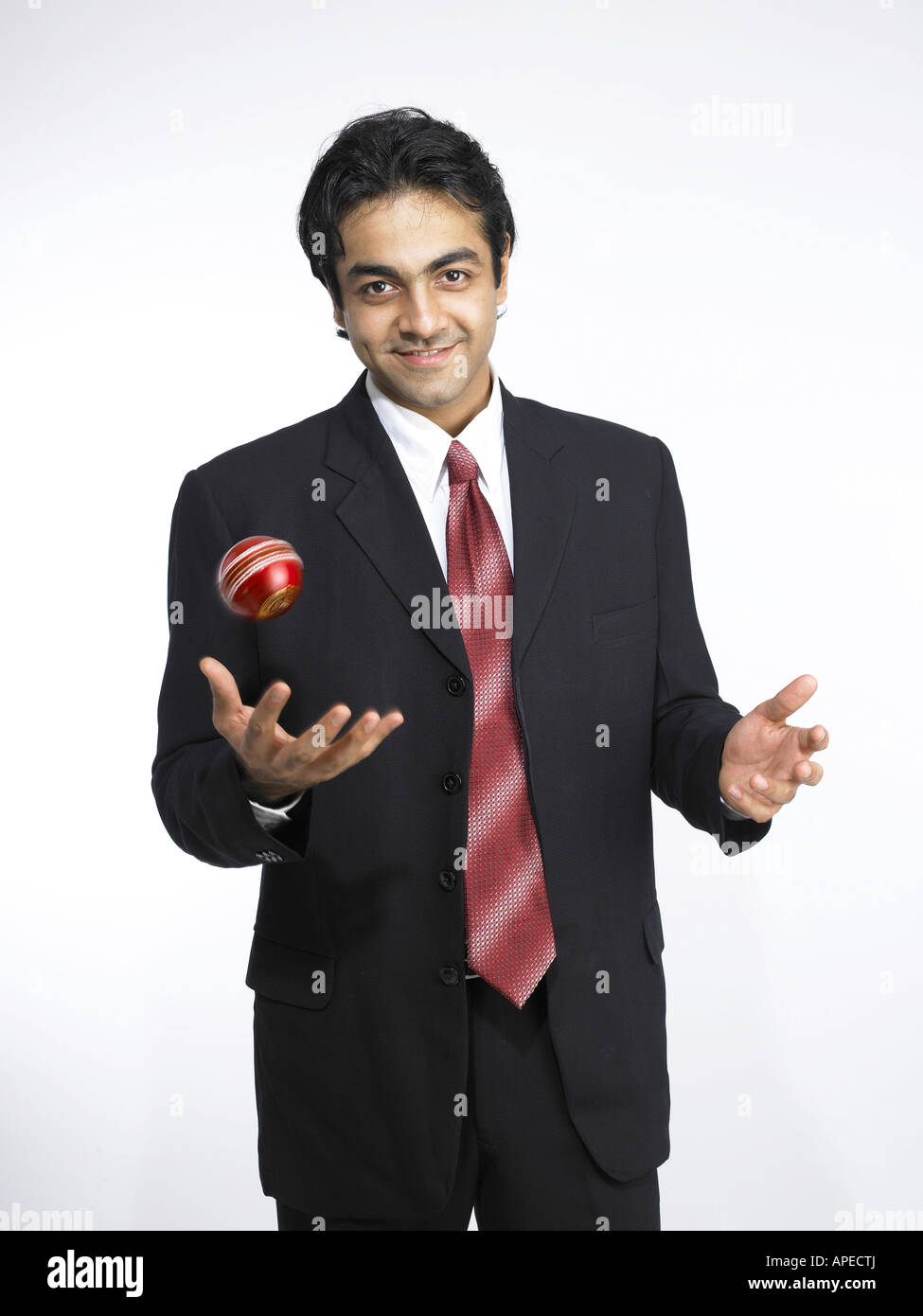 South Asian Indian executive throwing maroon color cricket ball Stock ...