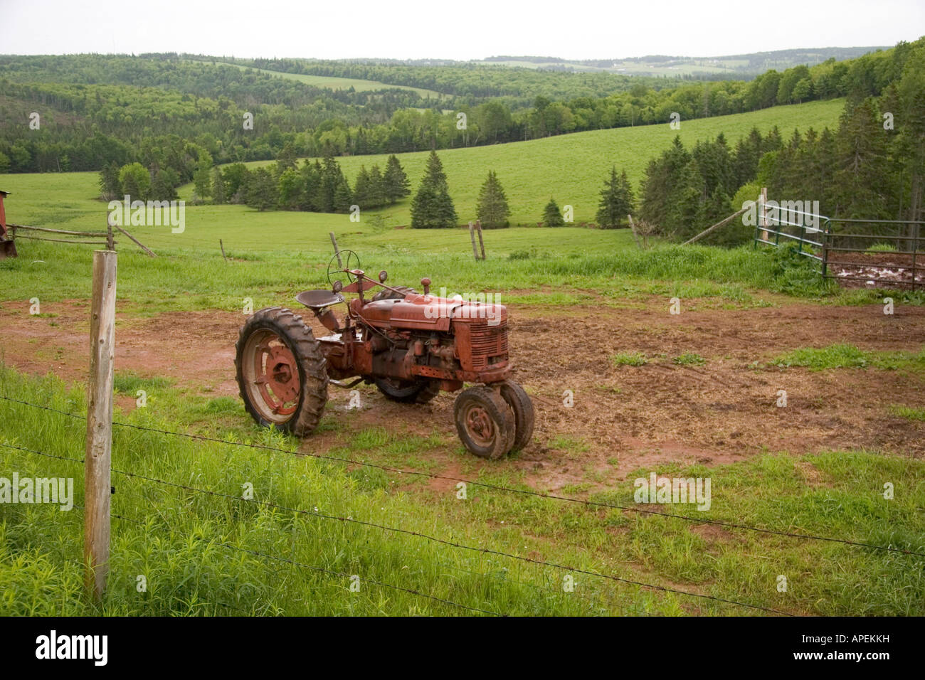 A tractor sits in a farm field on a misty rainy morning in springtime ...
