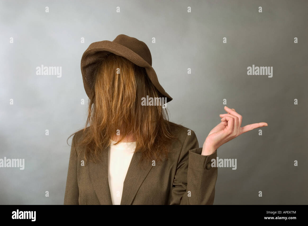 Woman, wearing a hat, pointing her finger while her long hair ...