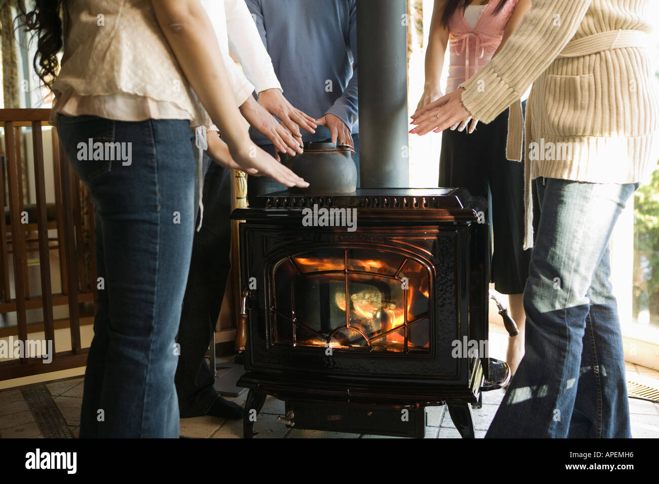 Friends Getting Warm Around a Wood Stove Stock Photo - Alamy
