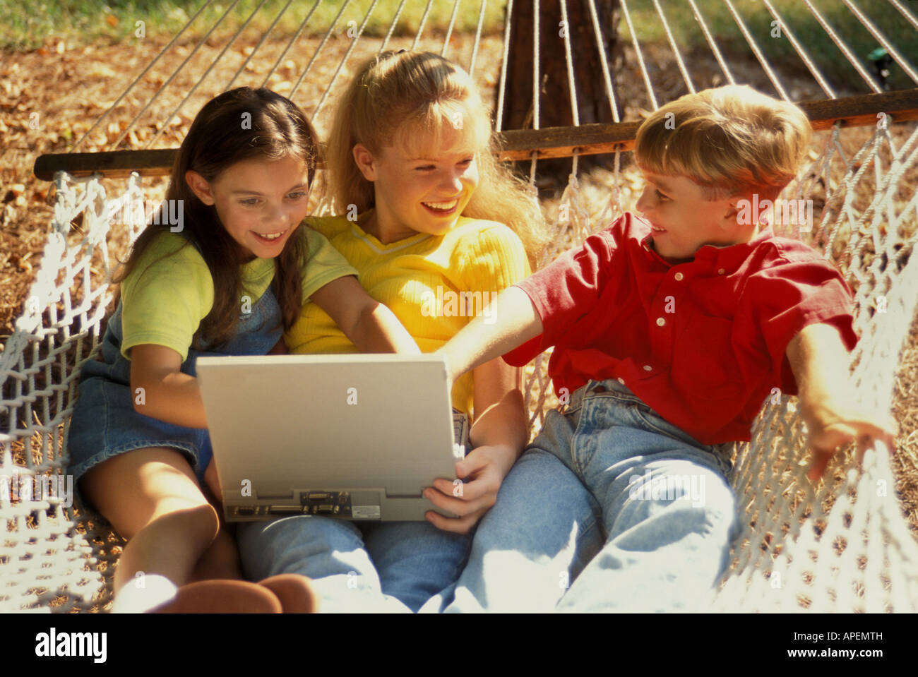 Teen shows children her laptop computer Stock Photo - Alamy