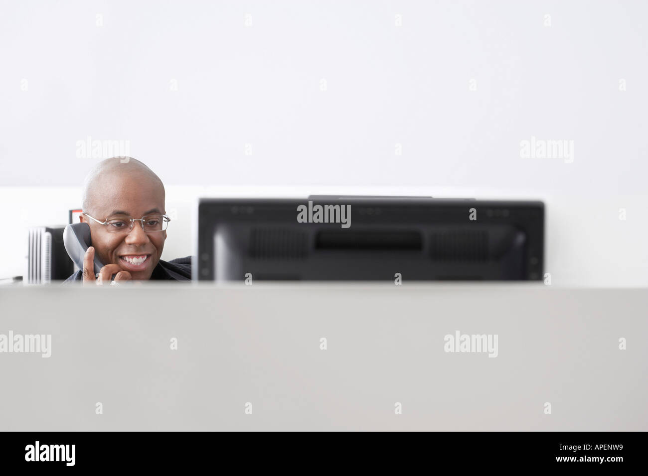 Office worker sitting in office cubicle using telephone, smiling Stock ...