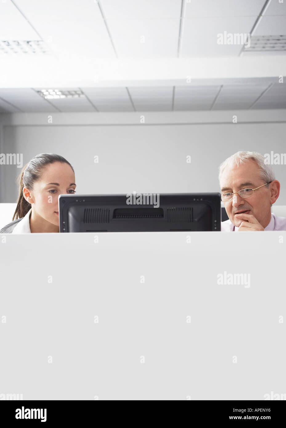 Two office workers looking at computer in office cubicle Stock Photo ...