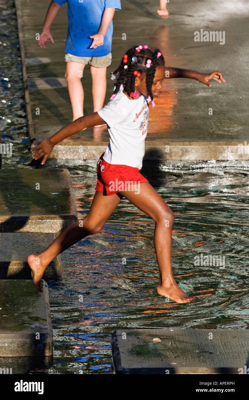 Pan Shot of Young Girl Jumping Across Stepping Stones in Fountain The ...