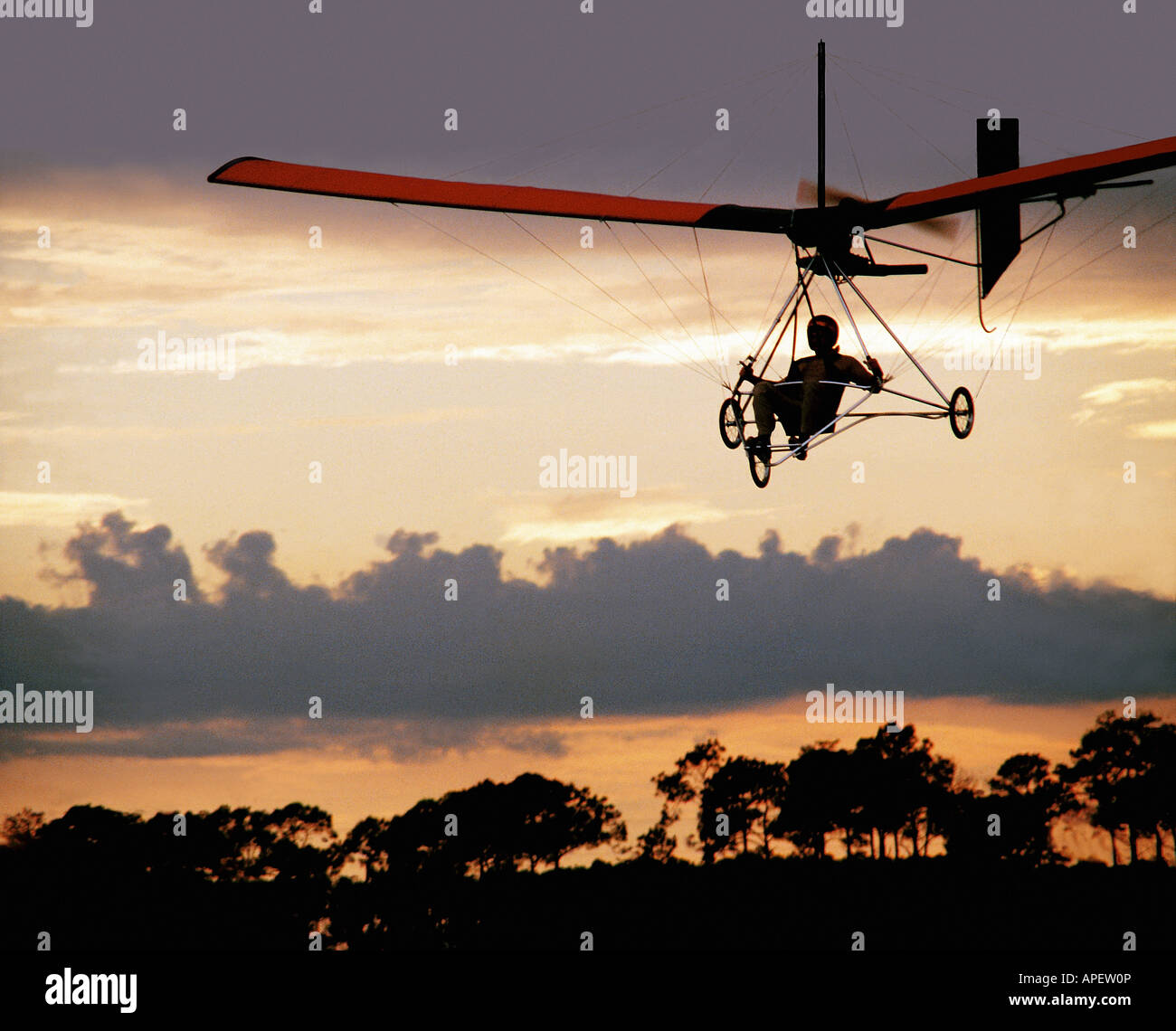 Ultralite flyer in silhouette with trees in sunset background Stock ...