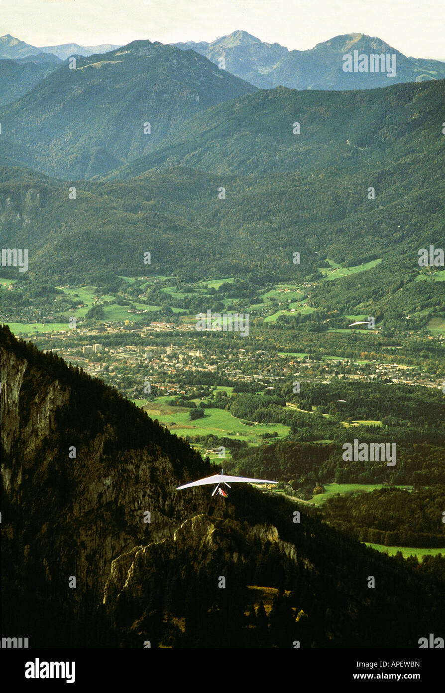 Parasailer soaring above green valley and mountains with sunset in ...