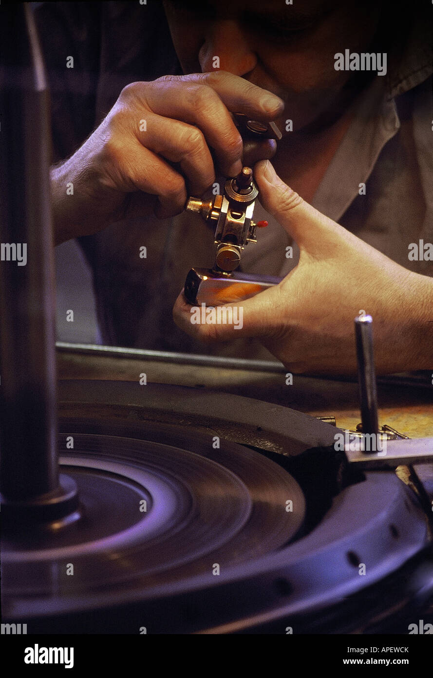 Jeweler's hands and head looking at jewel with instrument/magnifier ...