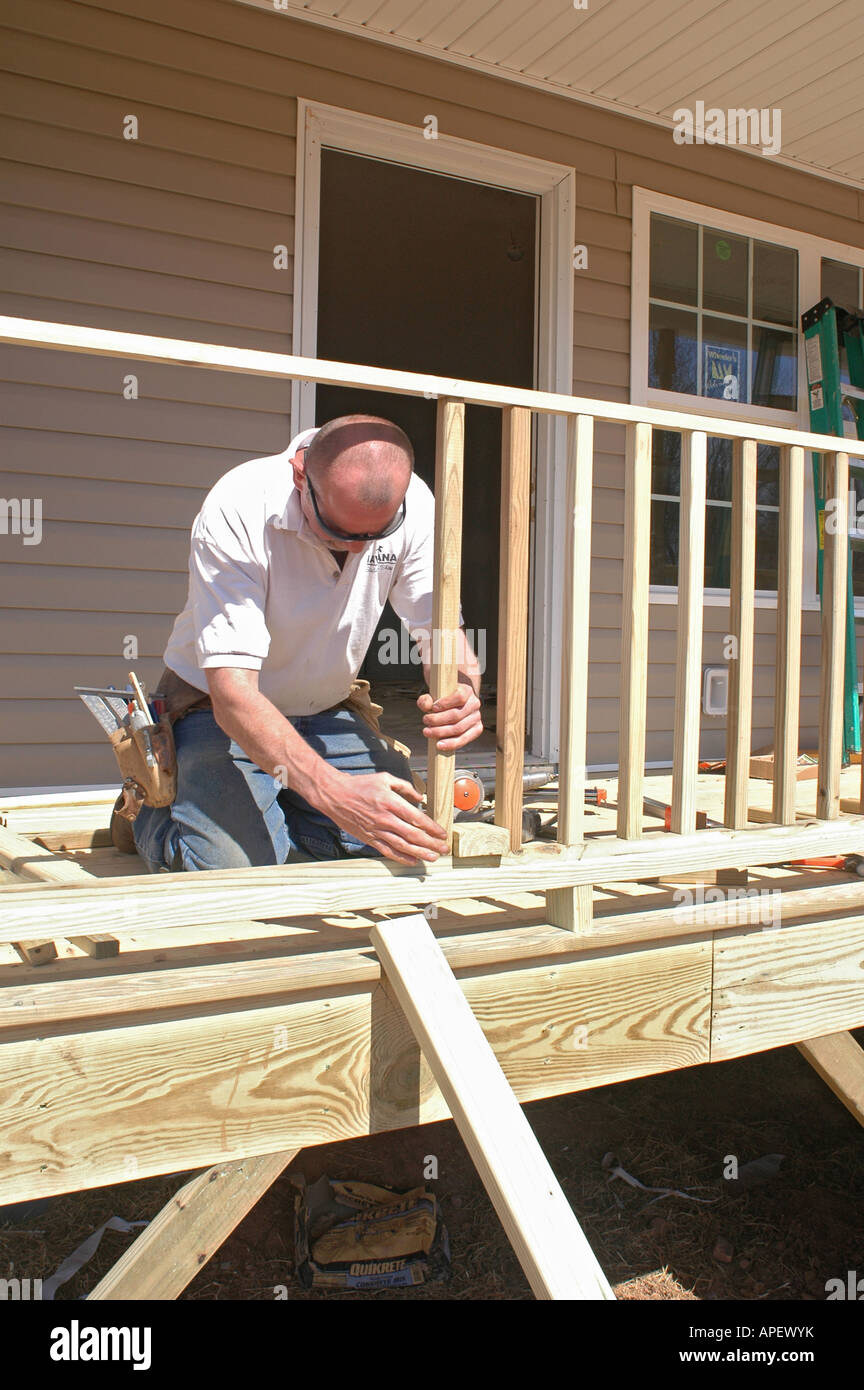 Construction worker building new family residence home deck railing ...