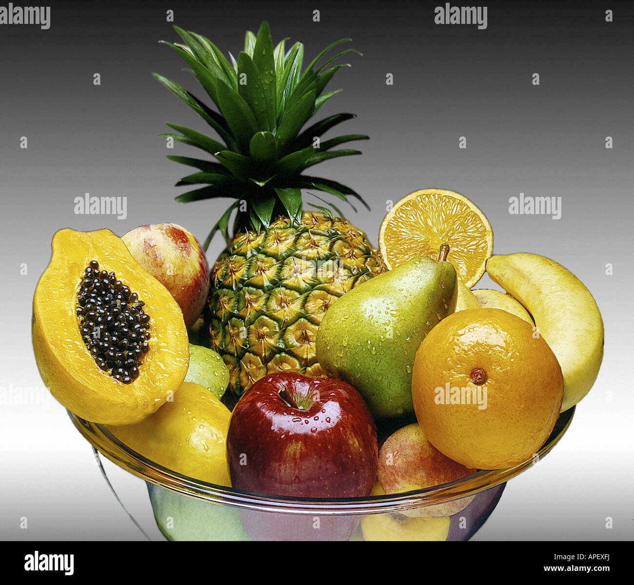 Studio close-up shot of varied tropical fruits in clear glass bowl ...