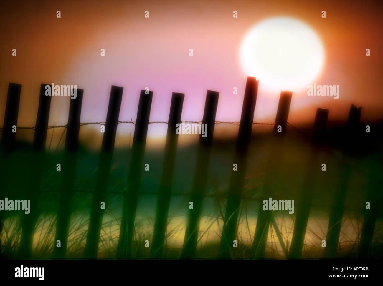 Slat wood fence in silhouette with fiery sun and sunset in background ...
