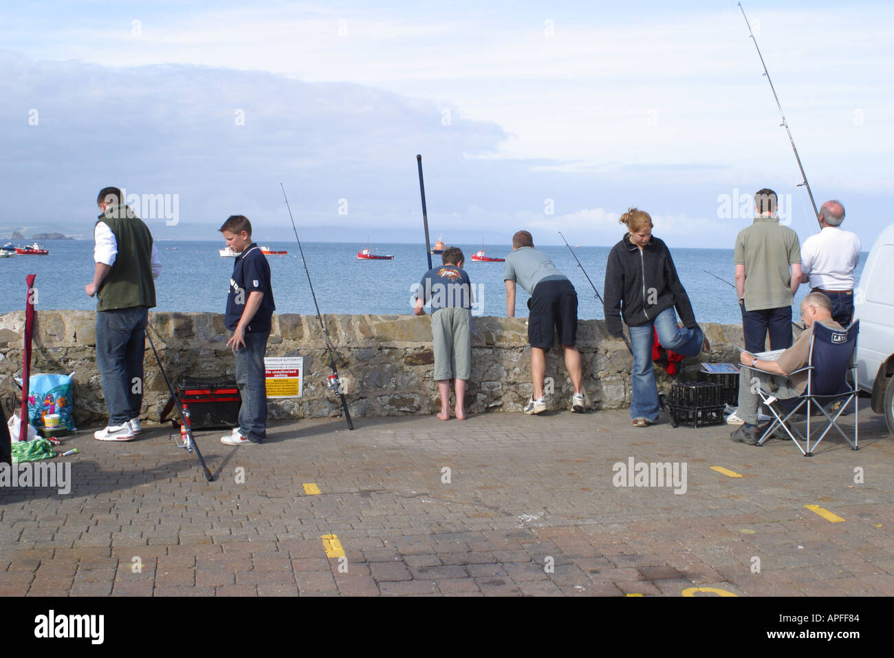 Anglers busy fishing in the sea from the harbour wall at Tenby ...