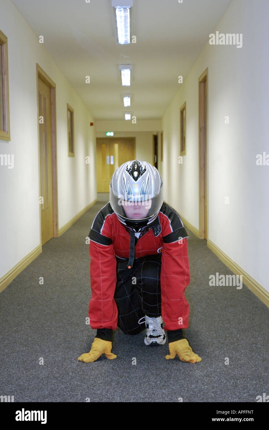 Girl in crash helmet crouching in ready position in office corridor ...