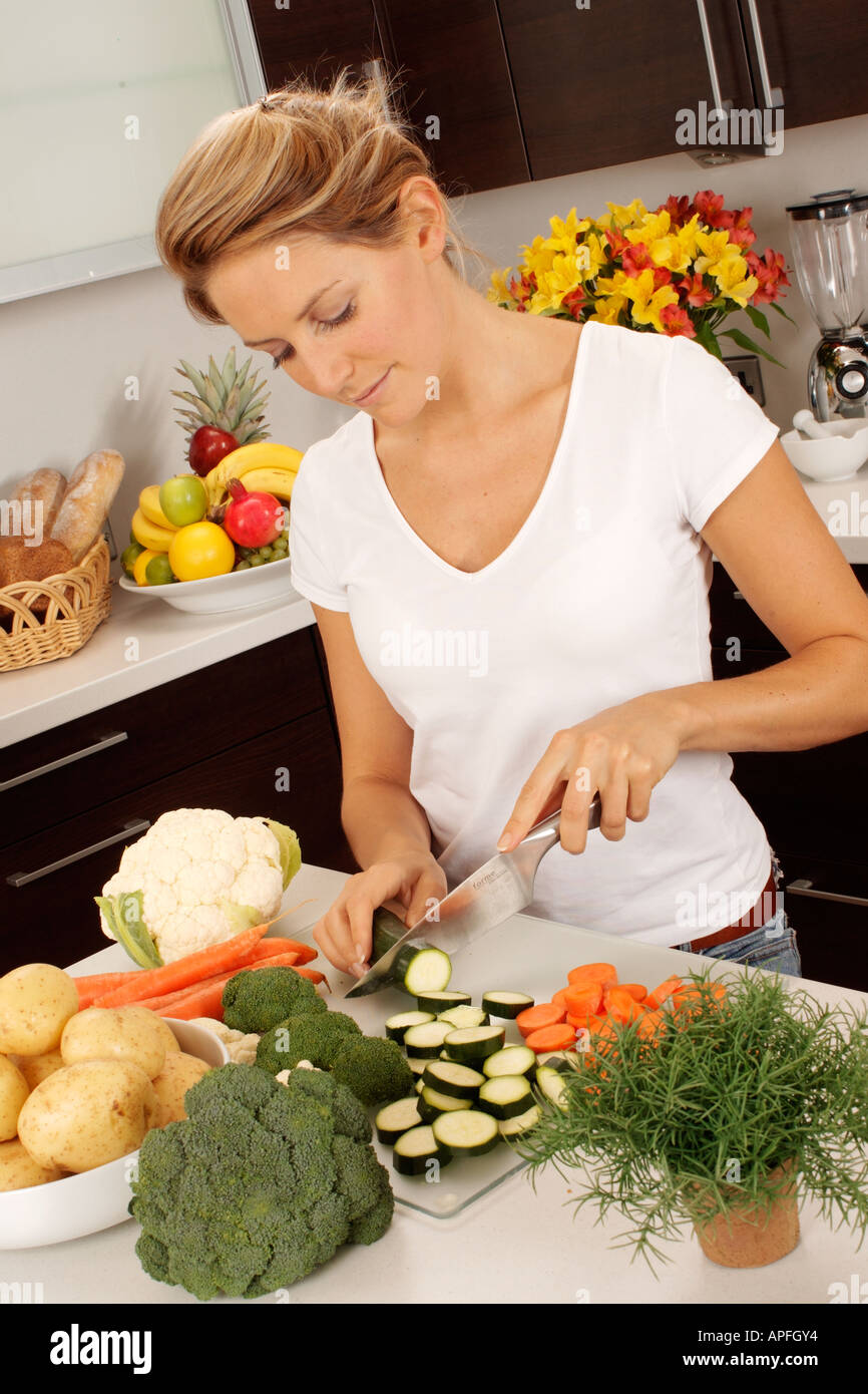 WOMAN IN KITCHEN CHOPPING COURGETTES / ZUCCHINI Stock Photo - Alamy