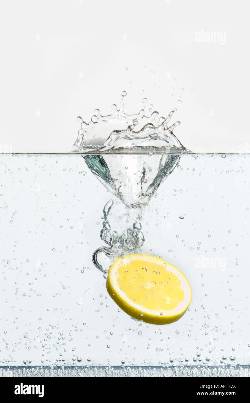 Slice of lemon splashing dropping into fizzy carbonated water Stock Photo - Alamy