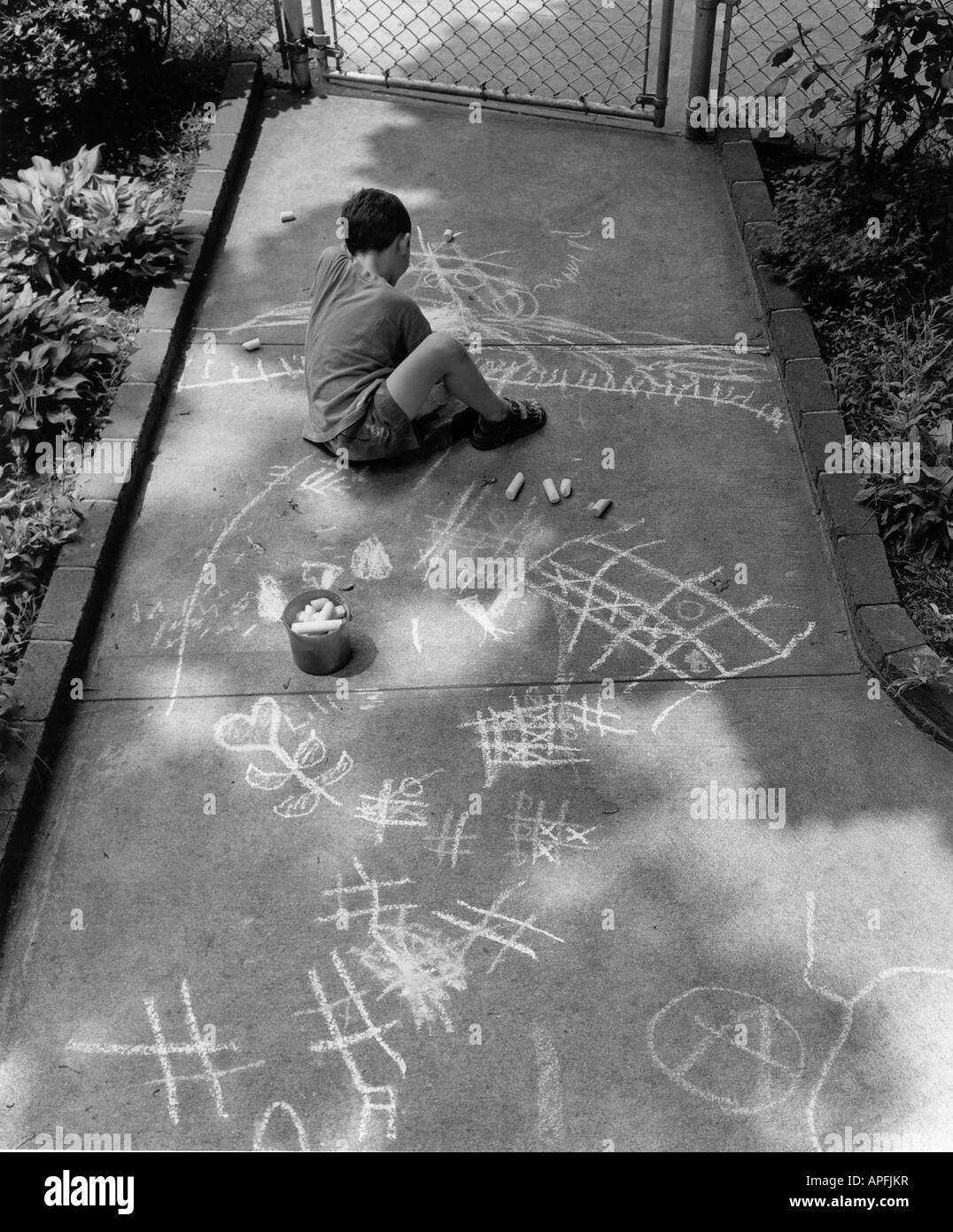 Young boy playing with chalk on his front walk in Brooklyn New York ...