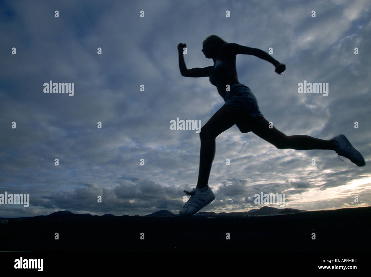 Woman running under storm clouds Stock Photo - Alamy
