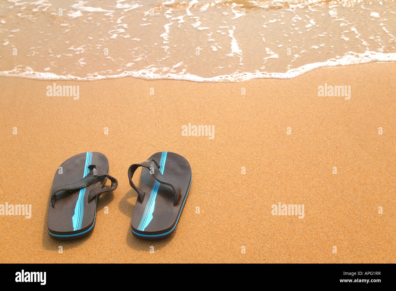 A pair of flip flops on a golden sandy beach by the waters edge Stock ...