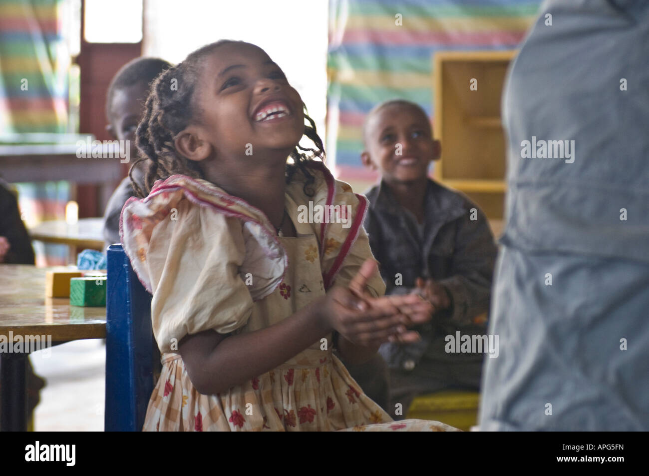 A young girl smiles at the teacher in the classroom of a charity run ...