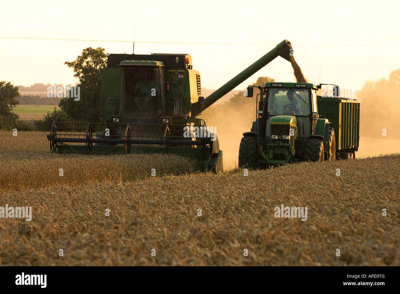 Combine Harvester unloading it's load of finished grain to a tractor ...