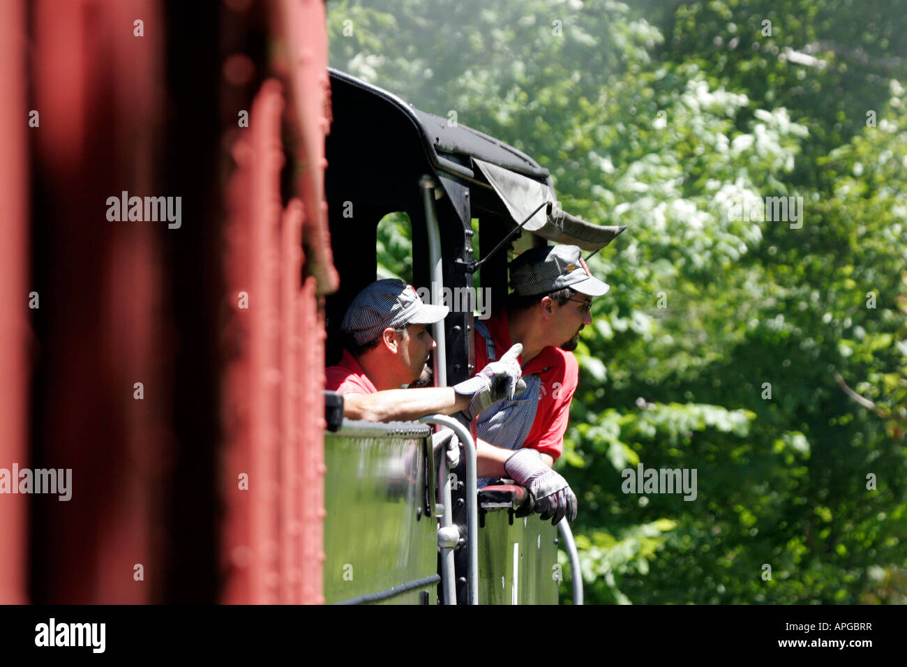 Two conductors hanging out the locomotive engine taking a break from ...