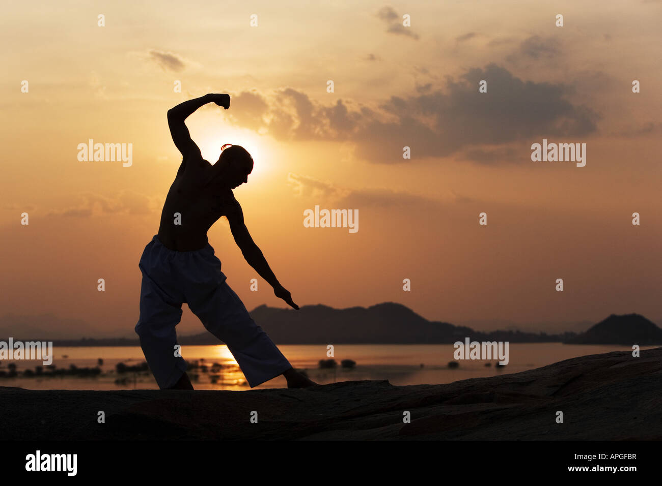 Man performing tai chi against a setting sun in india Stock Photo - Alamy