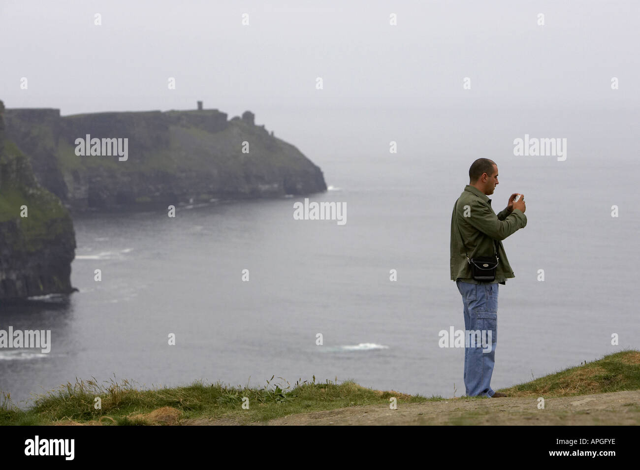 male tourist taking photos at the Cliffs of Moher County Clare Republic ...