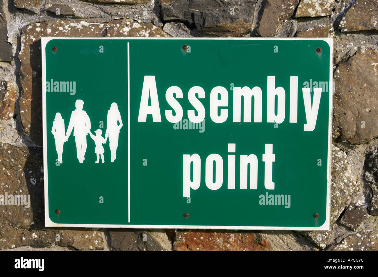 green and white assembly point safety sign depicting family on stone ...